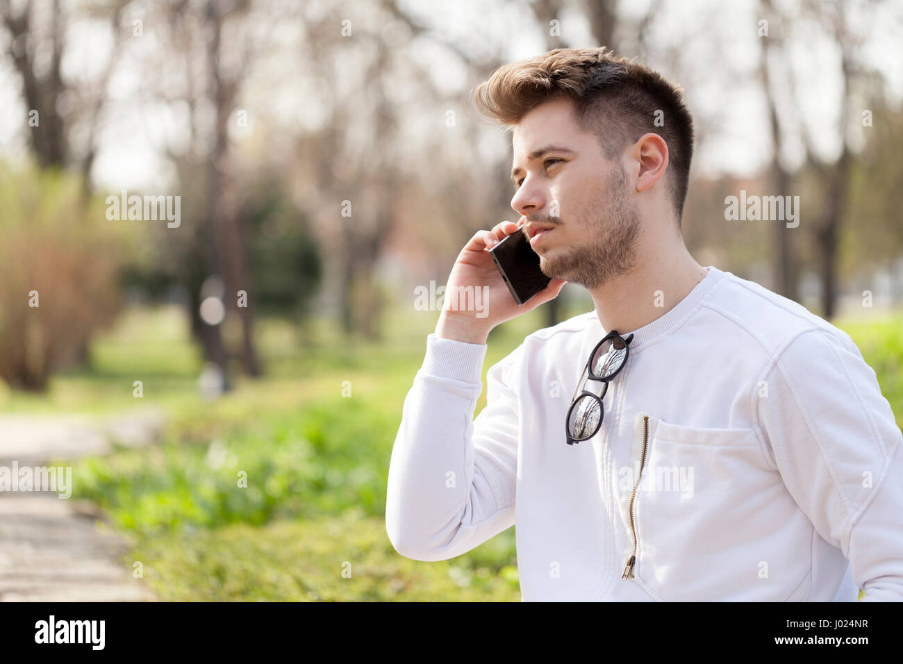 Handsome young man phoning and enjoys the outdoors. Selective focus and ...