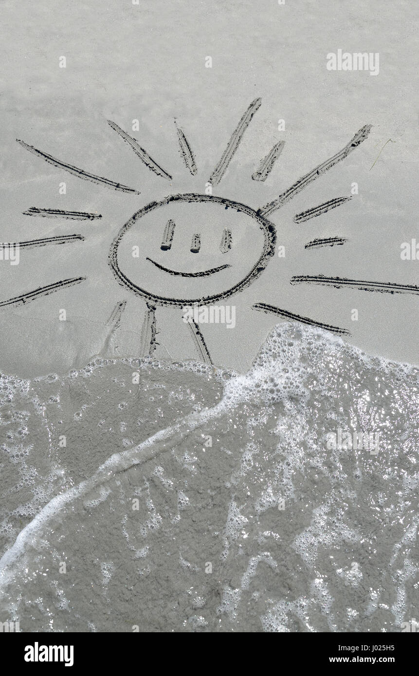 Drawing of the smiling sun in the sand Stock Photo - Alamy