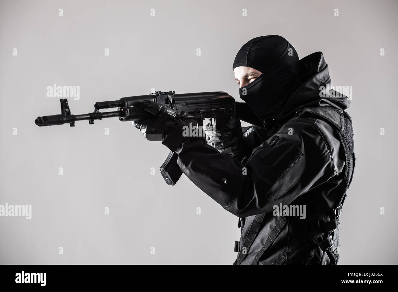 Terrorist aim with gun on isolated grey background Stock Photo - Alamy