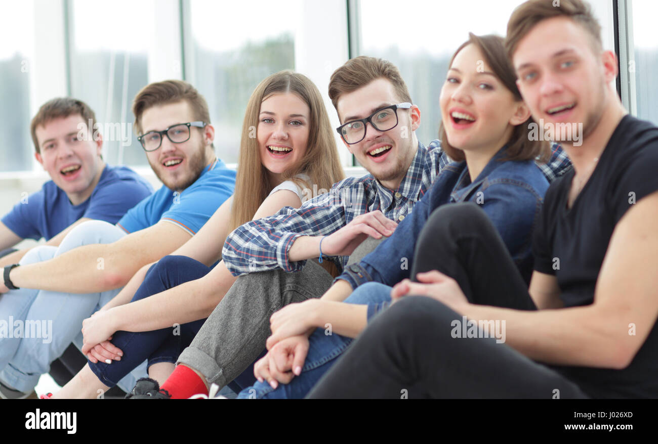 A group of happy students sitting on a window sill and smiling Stock ...