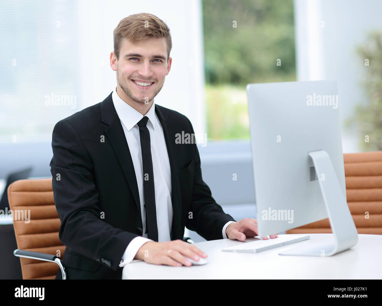 Smiling business man working on computer in a modern office Stock Photo ...
