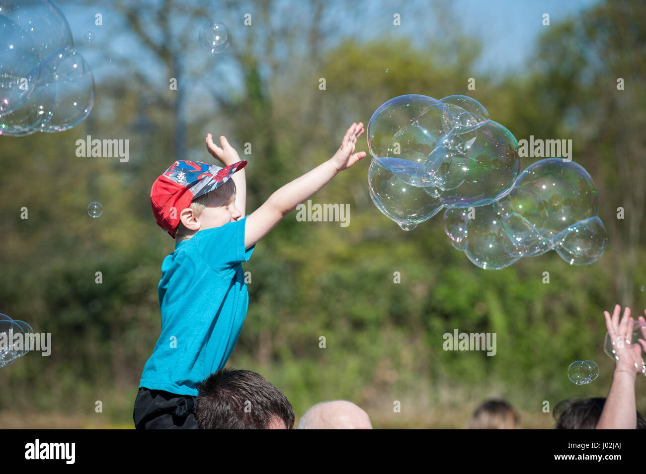 A young boy is lifted up into the air by his father so he can try and ...