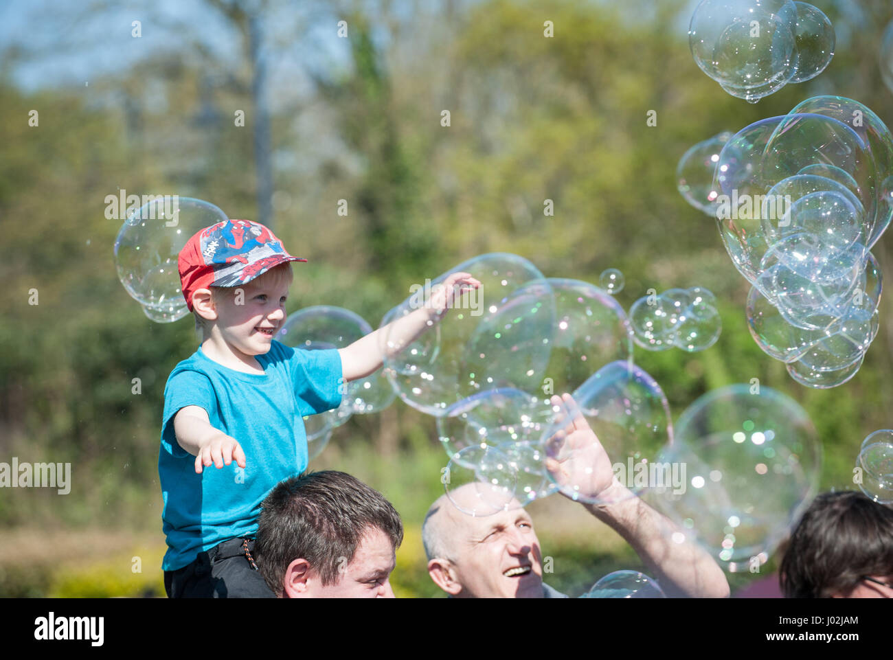 A young boy is lifted up into the air by his father so he can try and ...