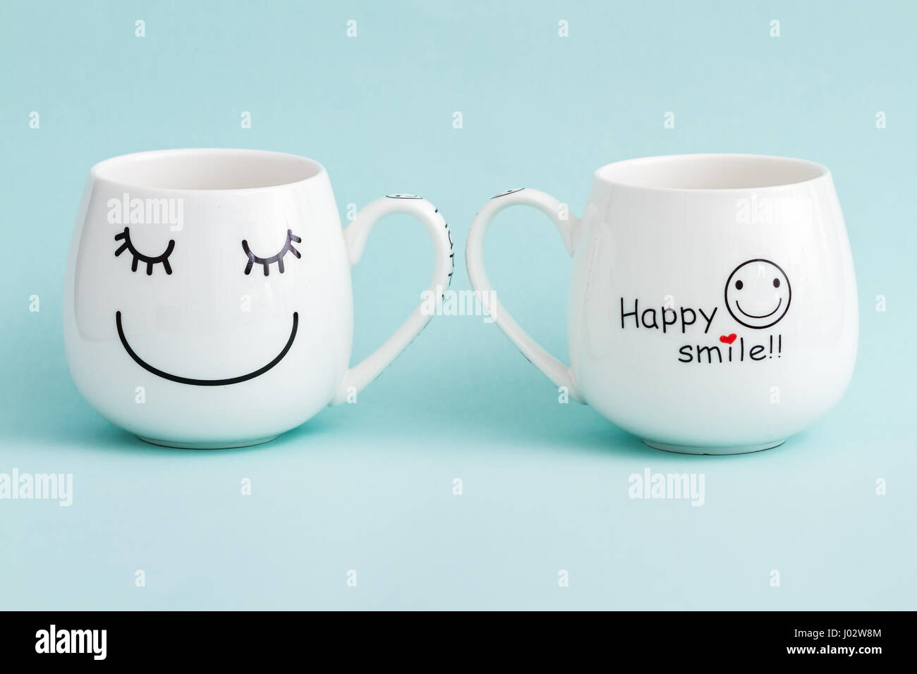 Smiling white coffee mugs on green background Stock Photo - Alamy