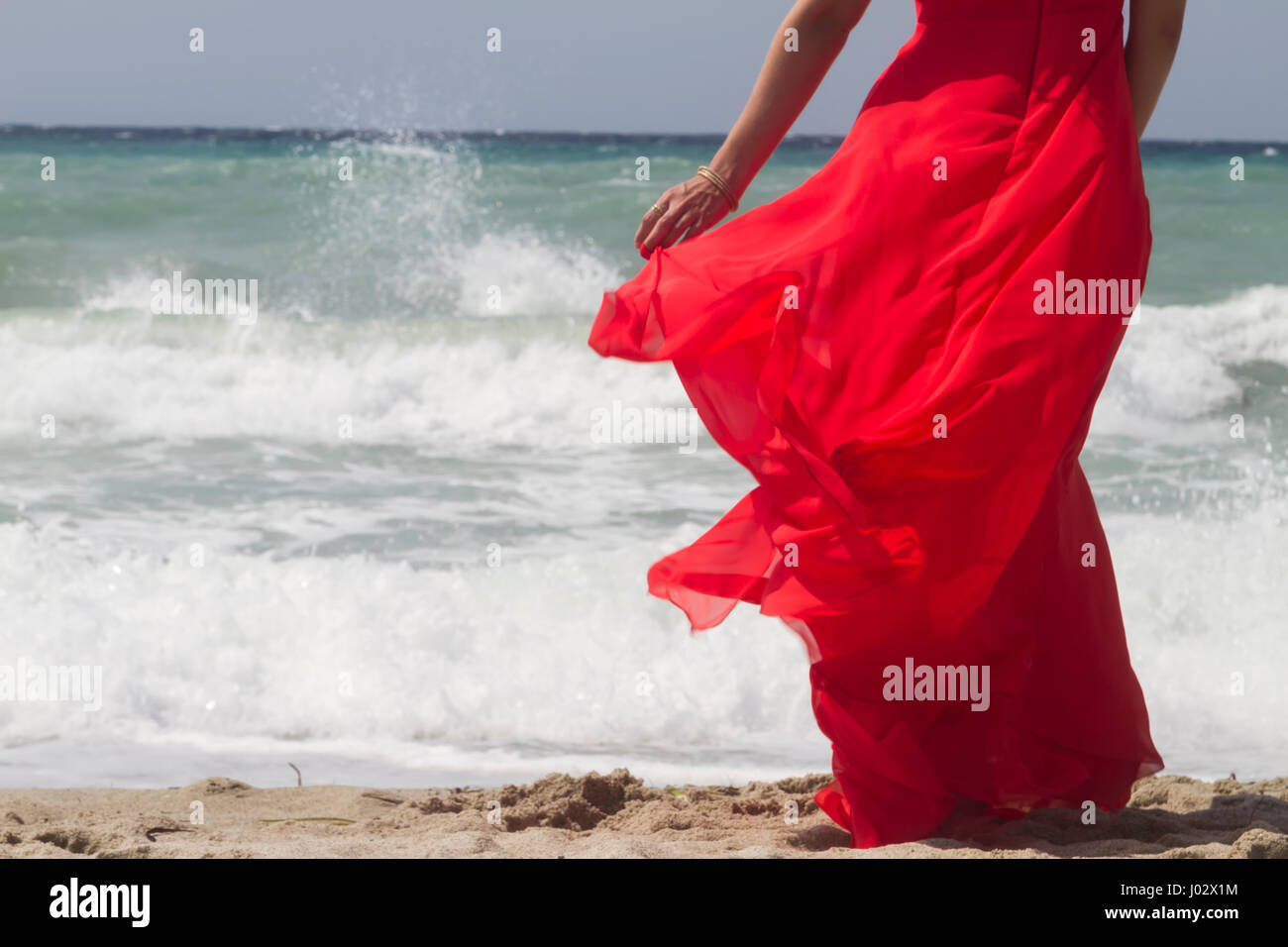 Beautiful red dress flowing in the wind at the beach. Cropped. Soft ...