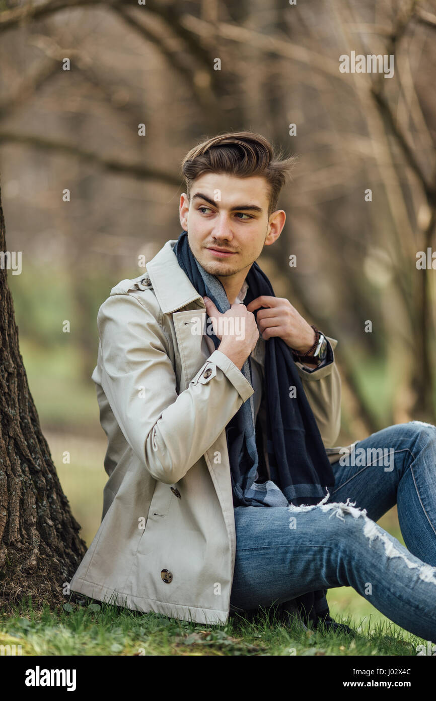 Fashionable man sitting near trees with blur background Stock Photo - Alamy