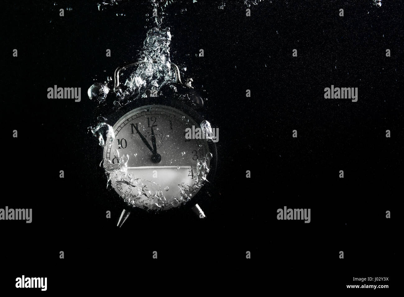 Alarm clock in water. Concept of time. Clock falls into the water with ...