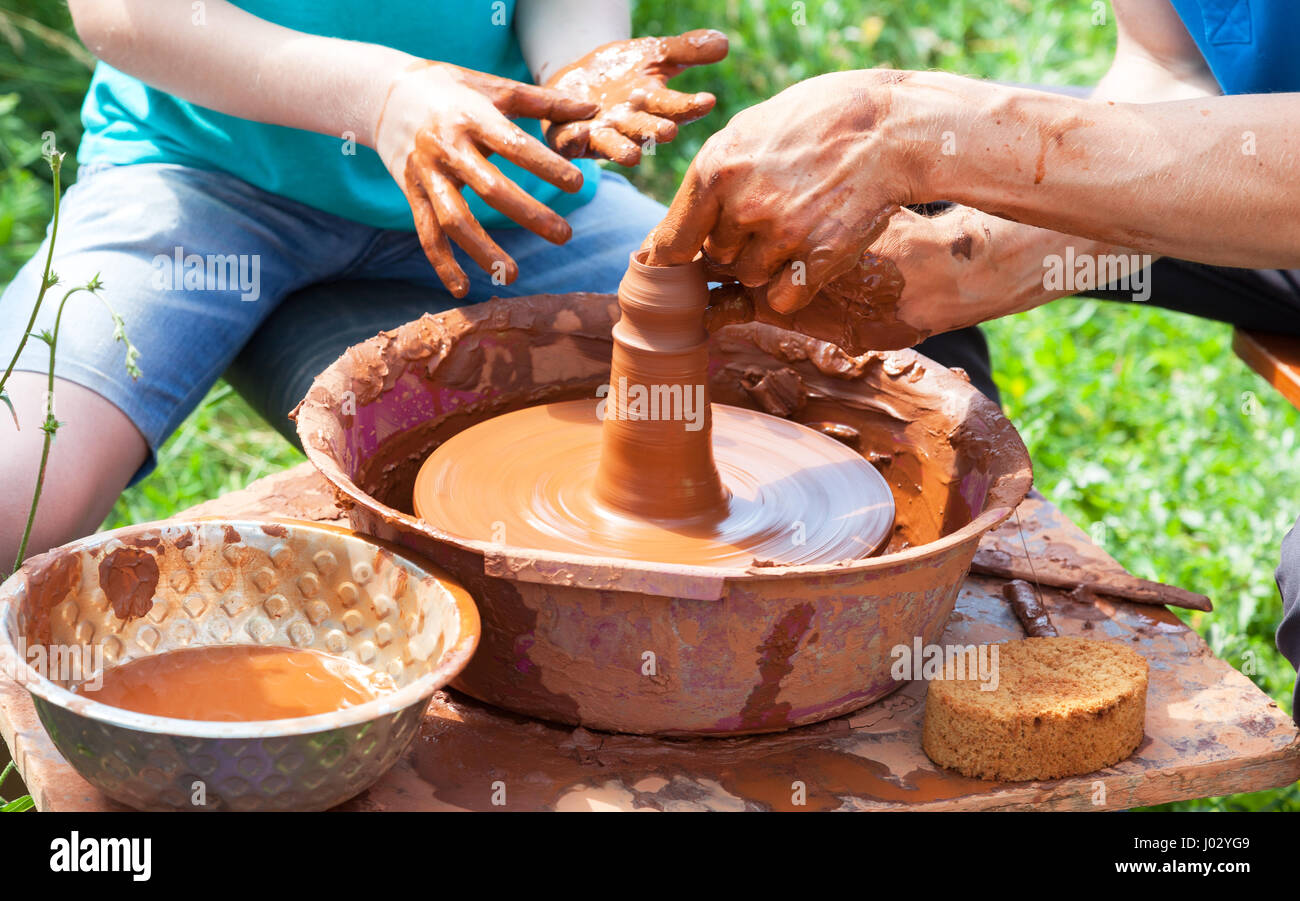 Teacher helps his student to work with red clay. Work on the potter's ...