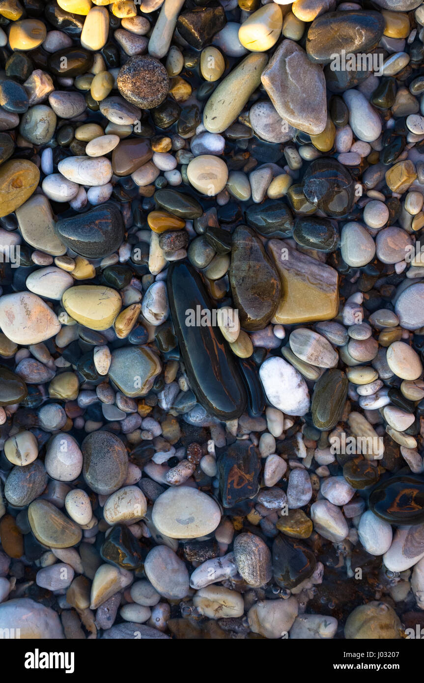 sea pebble beach with multicoloured stones, transparent waves with foam ...