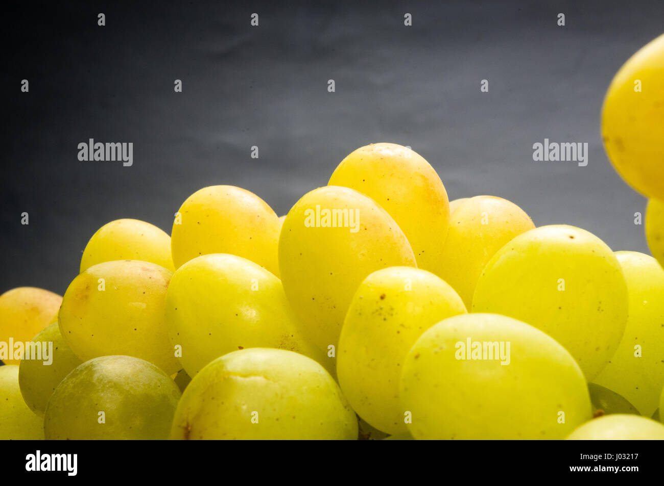 Large grapes cluster amber color on black background Stock Photo - Alamy
