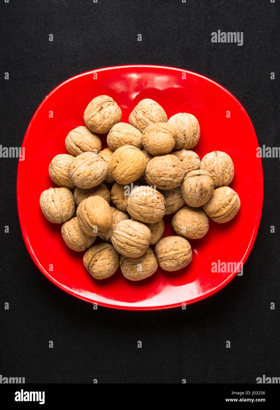 walnuts in red plate on black background Stock Photo - Alamy