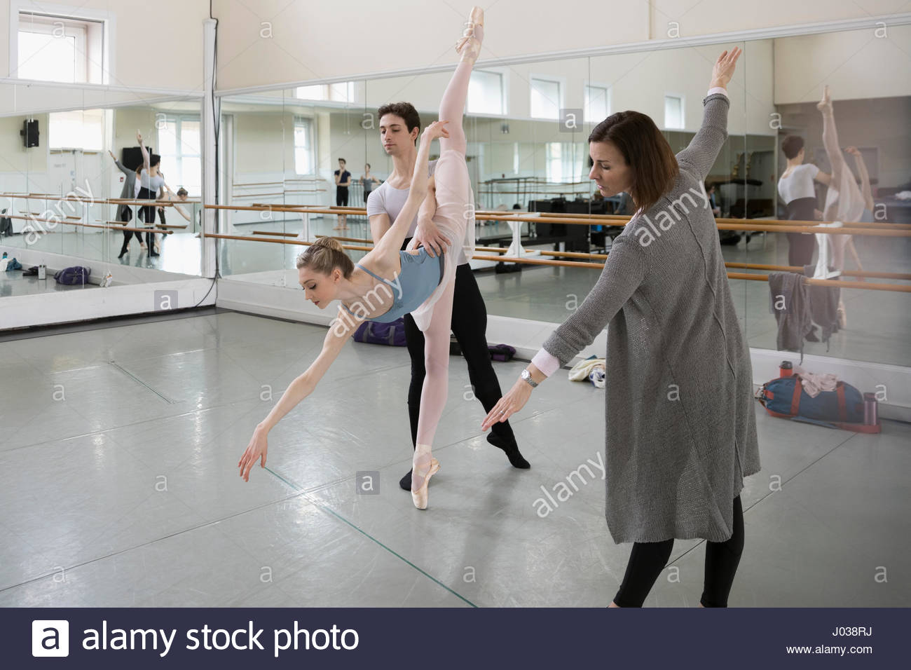 Instructor guiding ballet dancers practicing in dance studio Stock ...