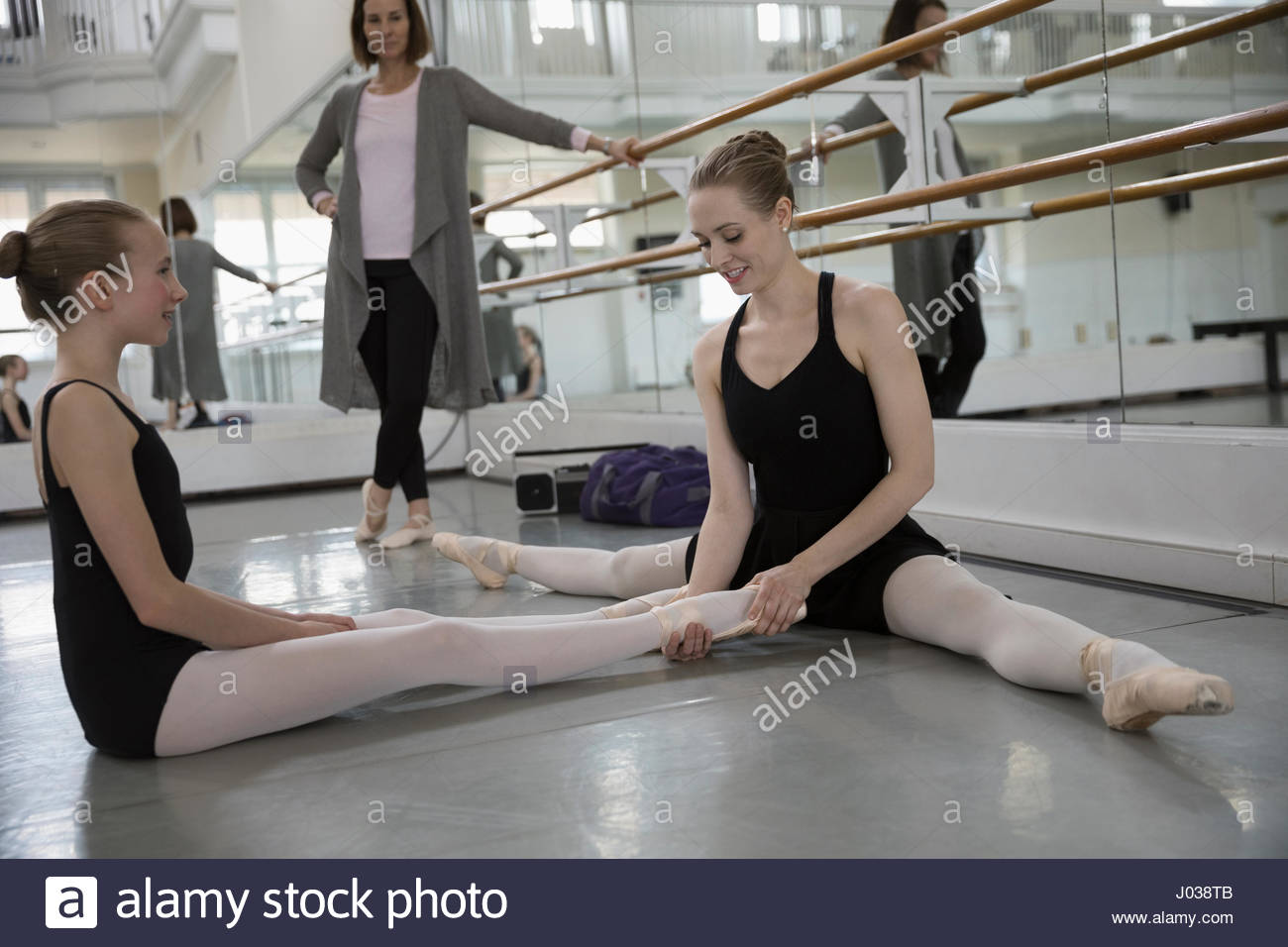 Female instructor stretching foot of ballet dancer prodigy in dance ...