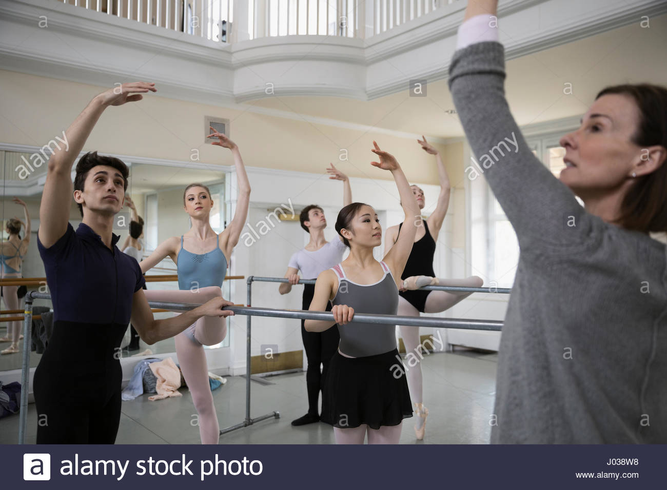 Instructor guiding ballet dancers practicing in dance studio Stock ...