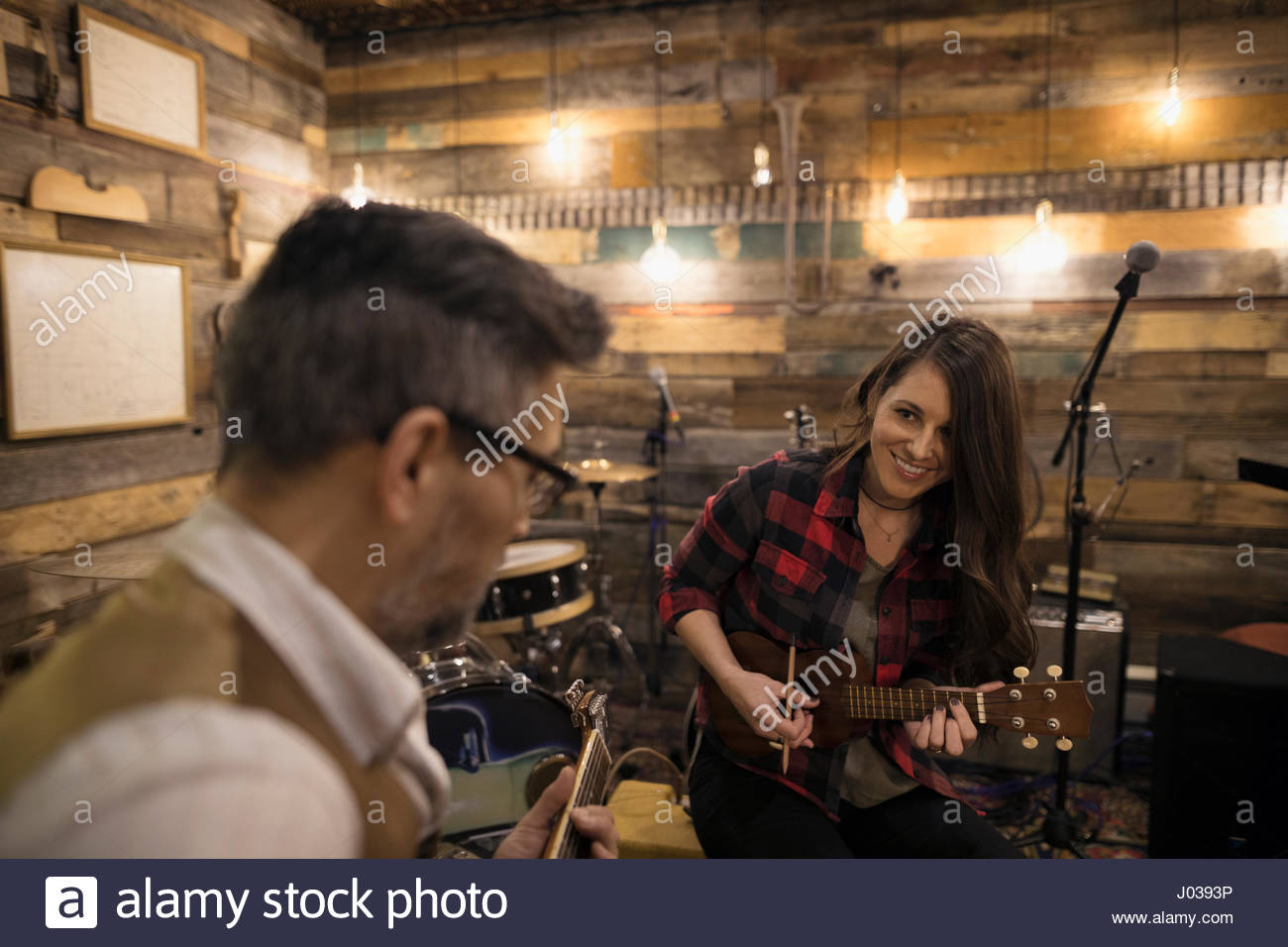Singer-songwriter musicians playing guitar and ukulele, writing music ...