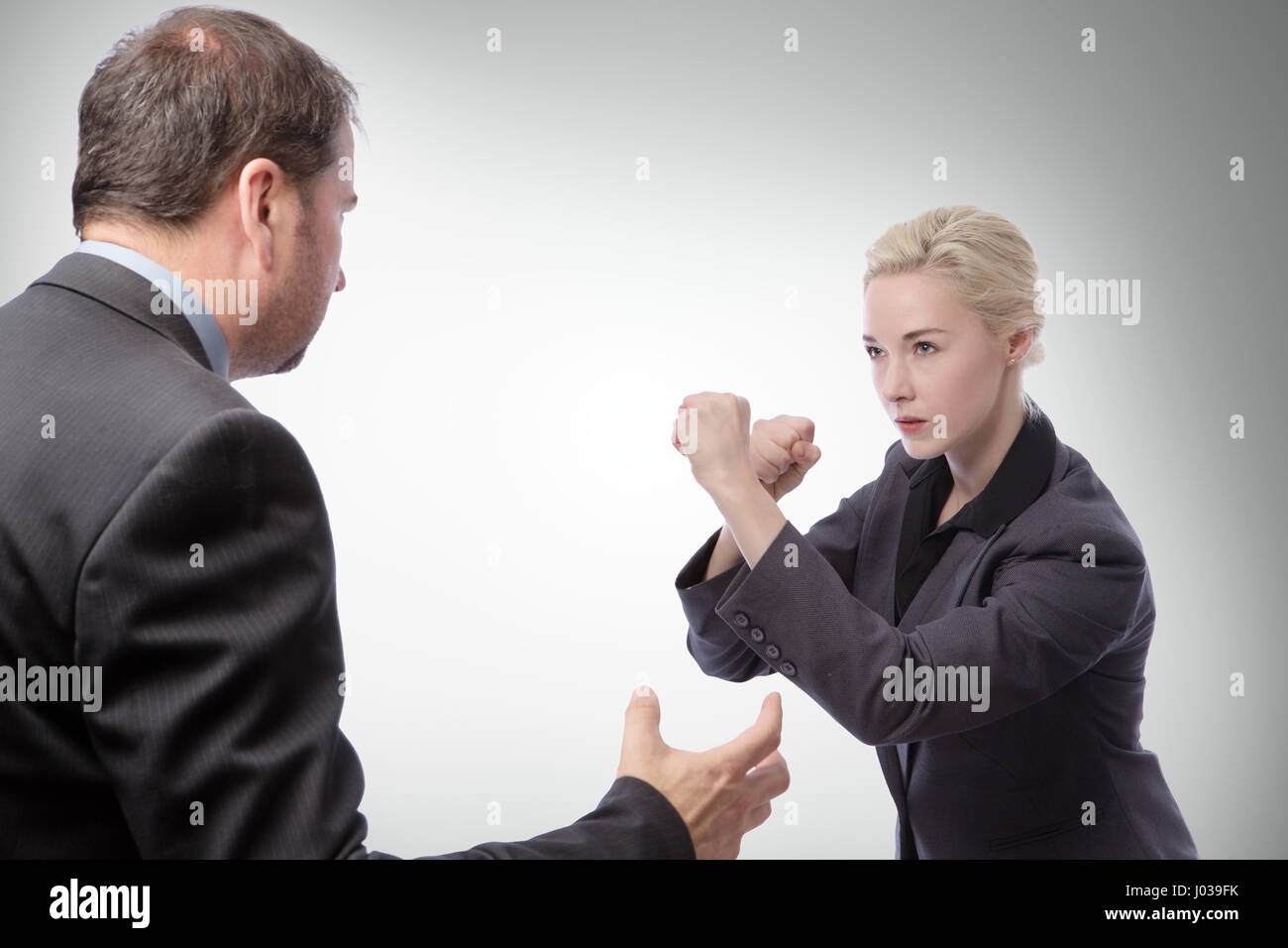 Studio shot of two co-workers wearing suits, fighting in the office ...