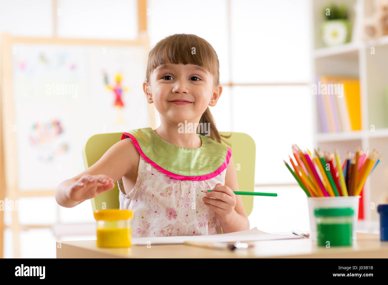 Cute preschooler child girl drawing with pencils in nursery Stock Photo ...