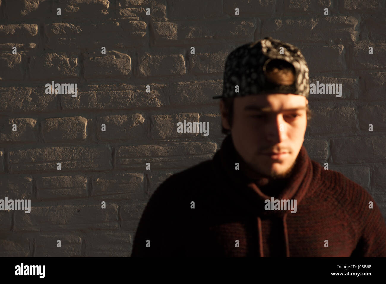 Handsome young guy in a baseball cap against brick wall background ...