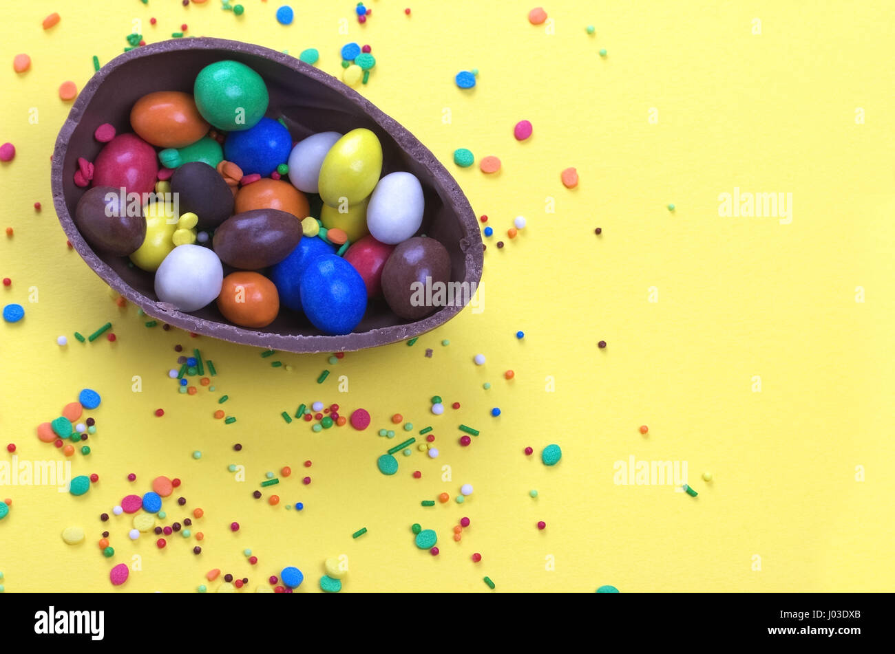 Easter chocolate egg with colorful explosion of candies and sweets on ...