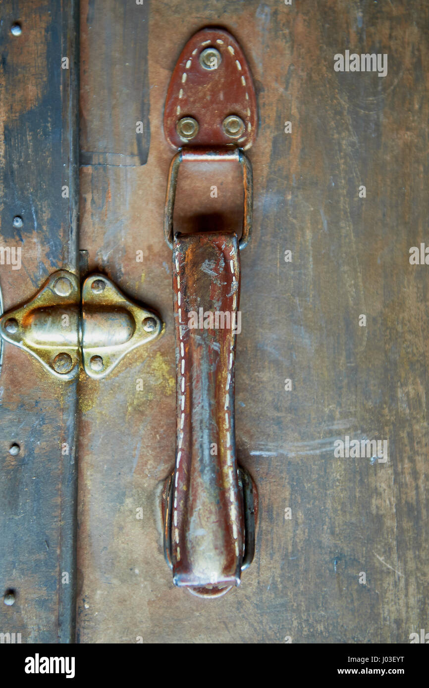 Old worn suitcase handle. Painted gold paint, base color is brown ...