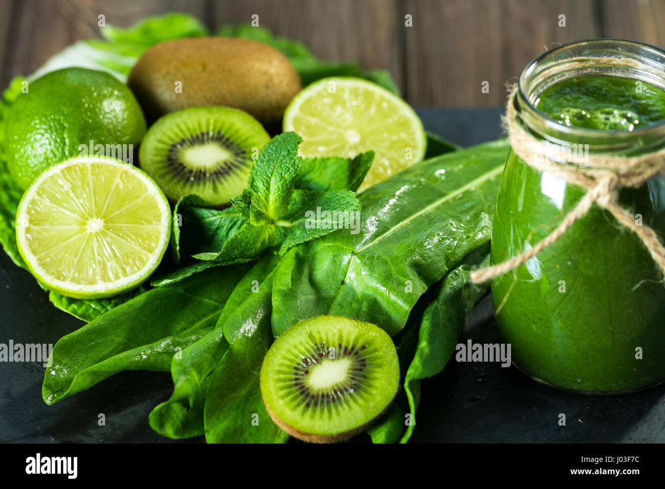 Blended green smoothie with ingredients on the stone board, wooden ...