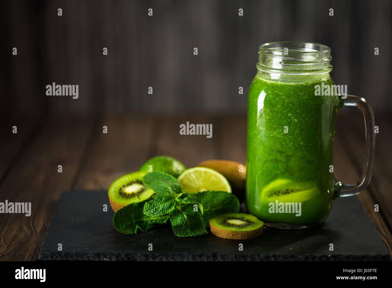 Blended green smoothie with ingredients on the stone board, wooden ...