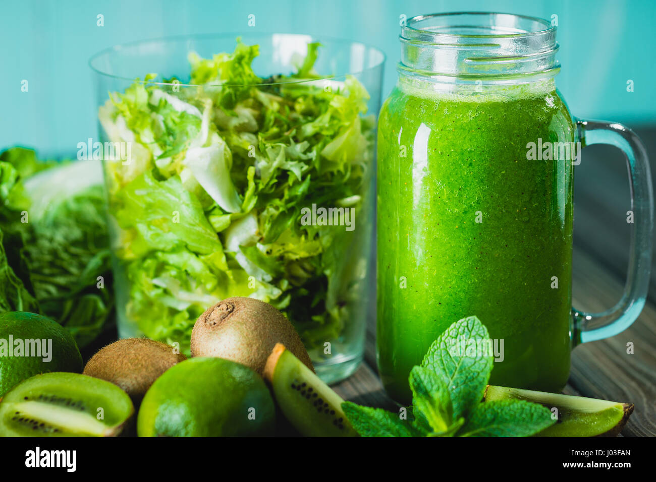 Blended green smoothie with ingredients on wooden table selective focus ...