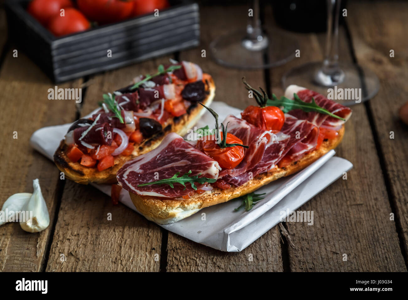 Toasts with jerky meat on a piece of paper. Rustic surface of wooden ...