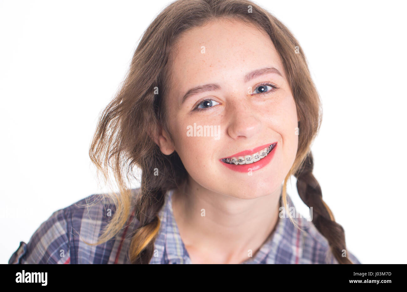 A cute piggy girl in a checkered shirt shows her braces. Isolated on ...
