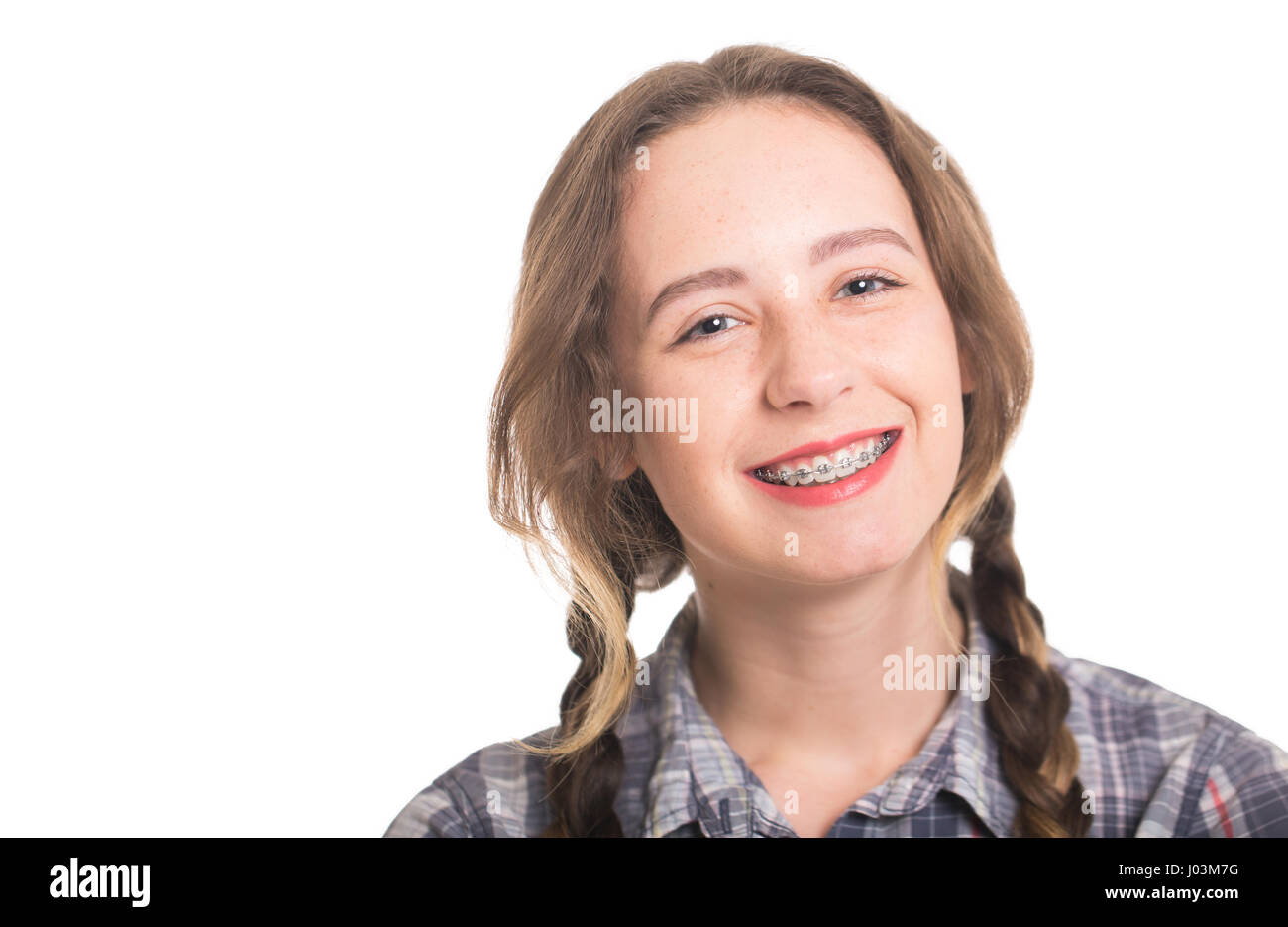 A cute piggy girl in a checkered shirt shows her braces. Isolated on ...