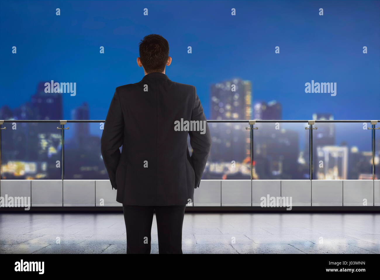 Back view of asian businessman looking at the city through window at ...