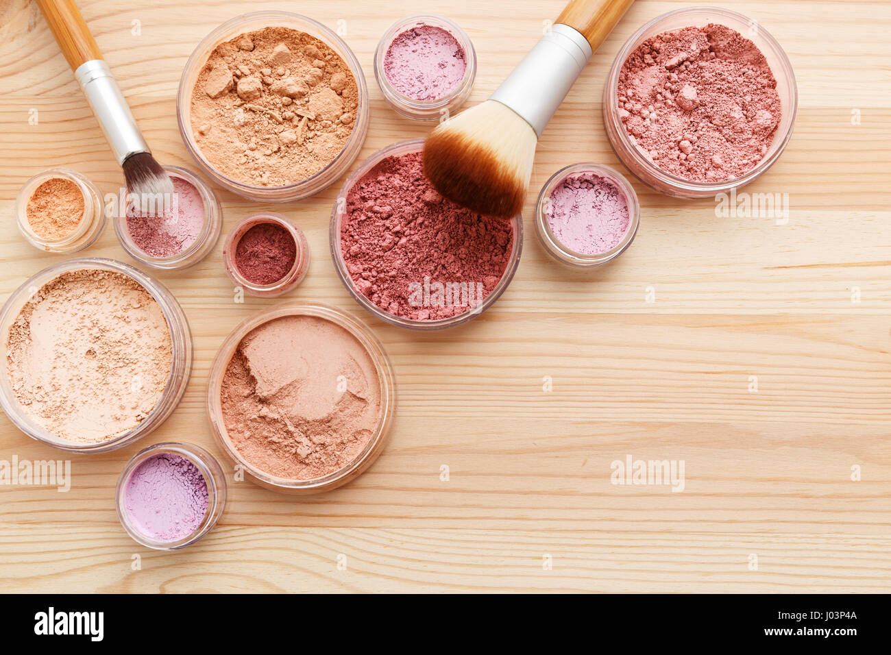 Makeup powder products with brushes on wood background Stock Photo - Alamy