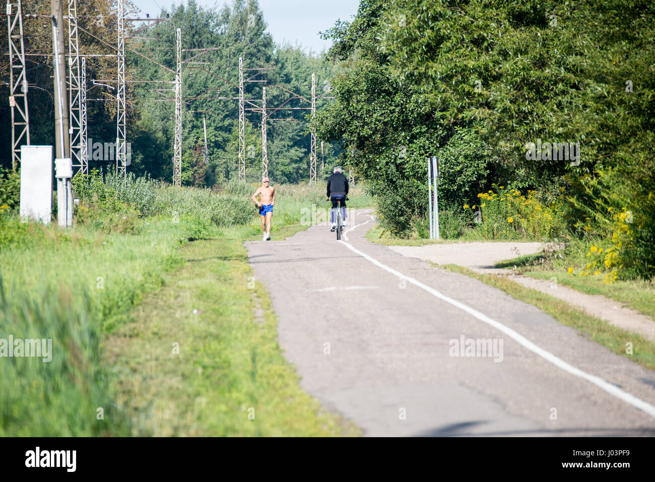 man jogging and man cycling on the road Stock Photo - Alamy