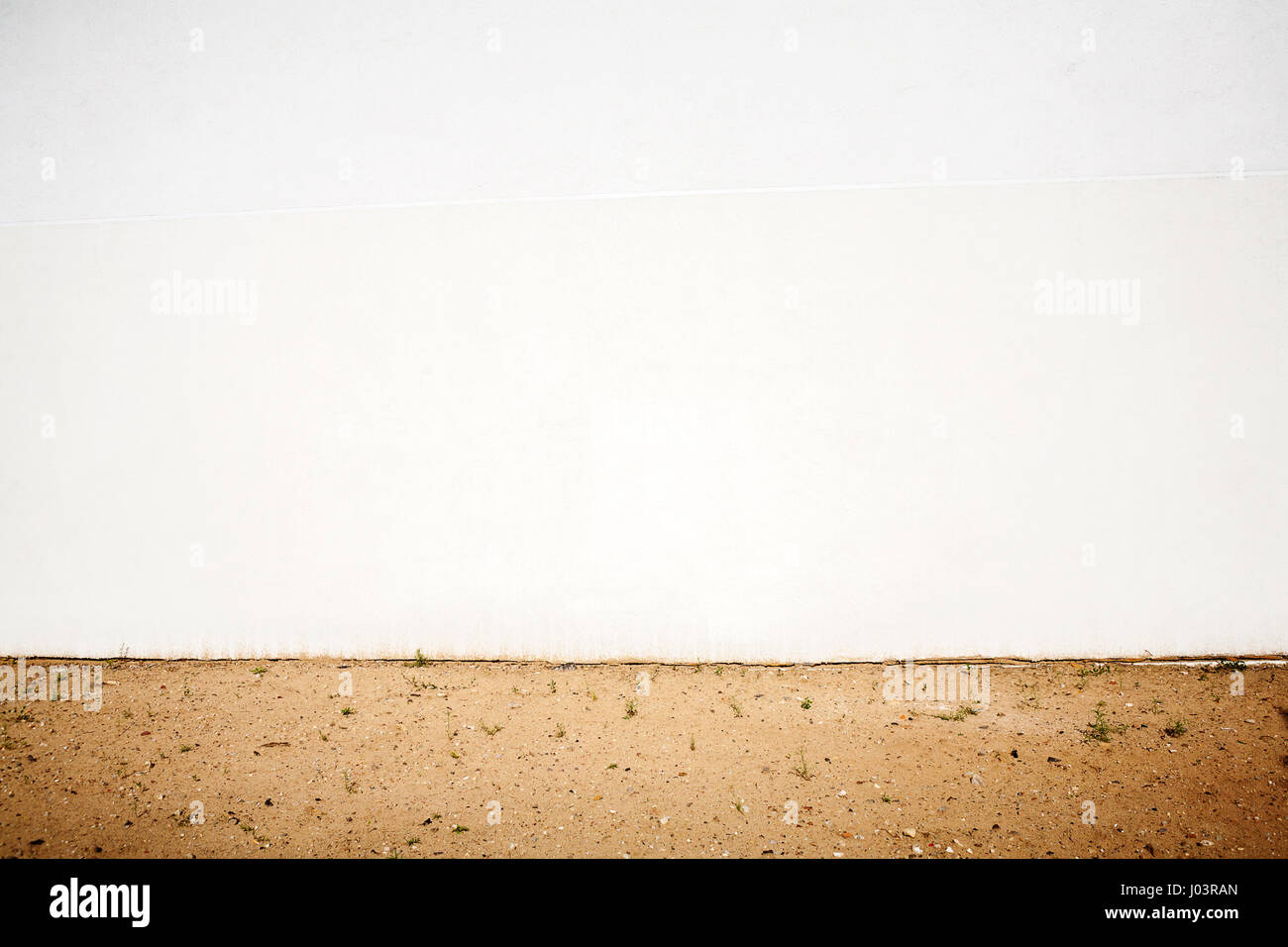 New white plaster wall and a ground covered with sand Stock Photo - Alamy