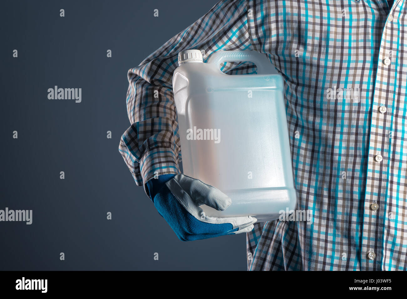 Unrecognizable male farmer with unlabeled plastic tank canister ...