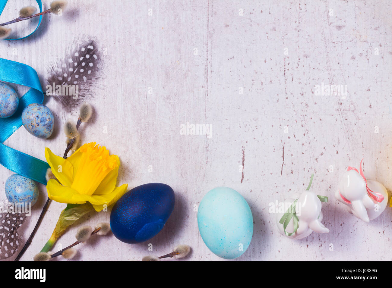 Easter border with painted blue eggs, rabbits and flowers on aged ...