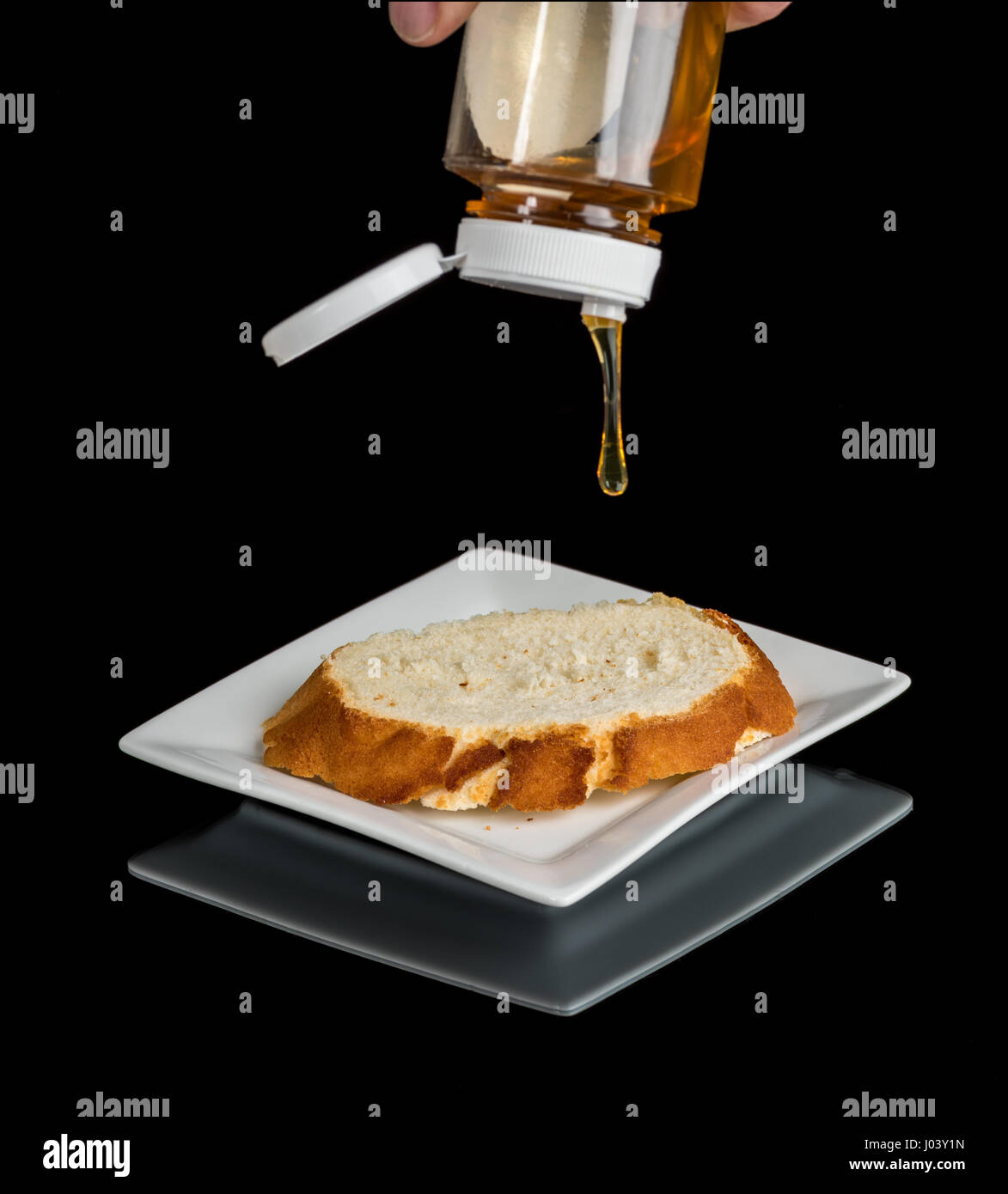 Bottle of honey squeezed onto a slice of bread Stock Photo - Alamy