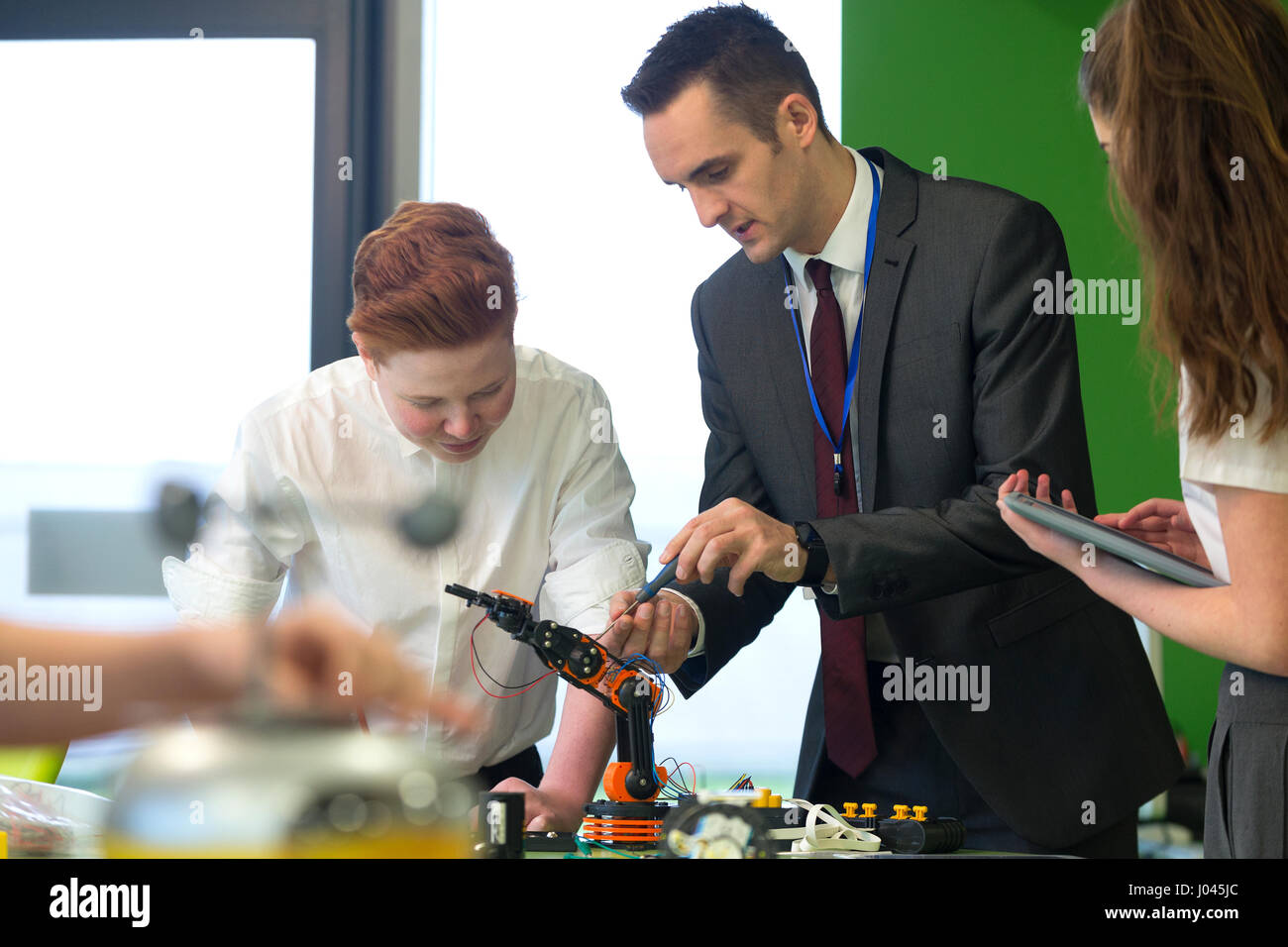 Two students are building a robotic arm in school. The teacher is ...