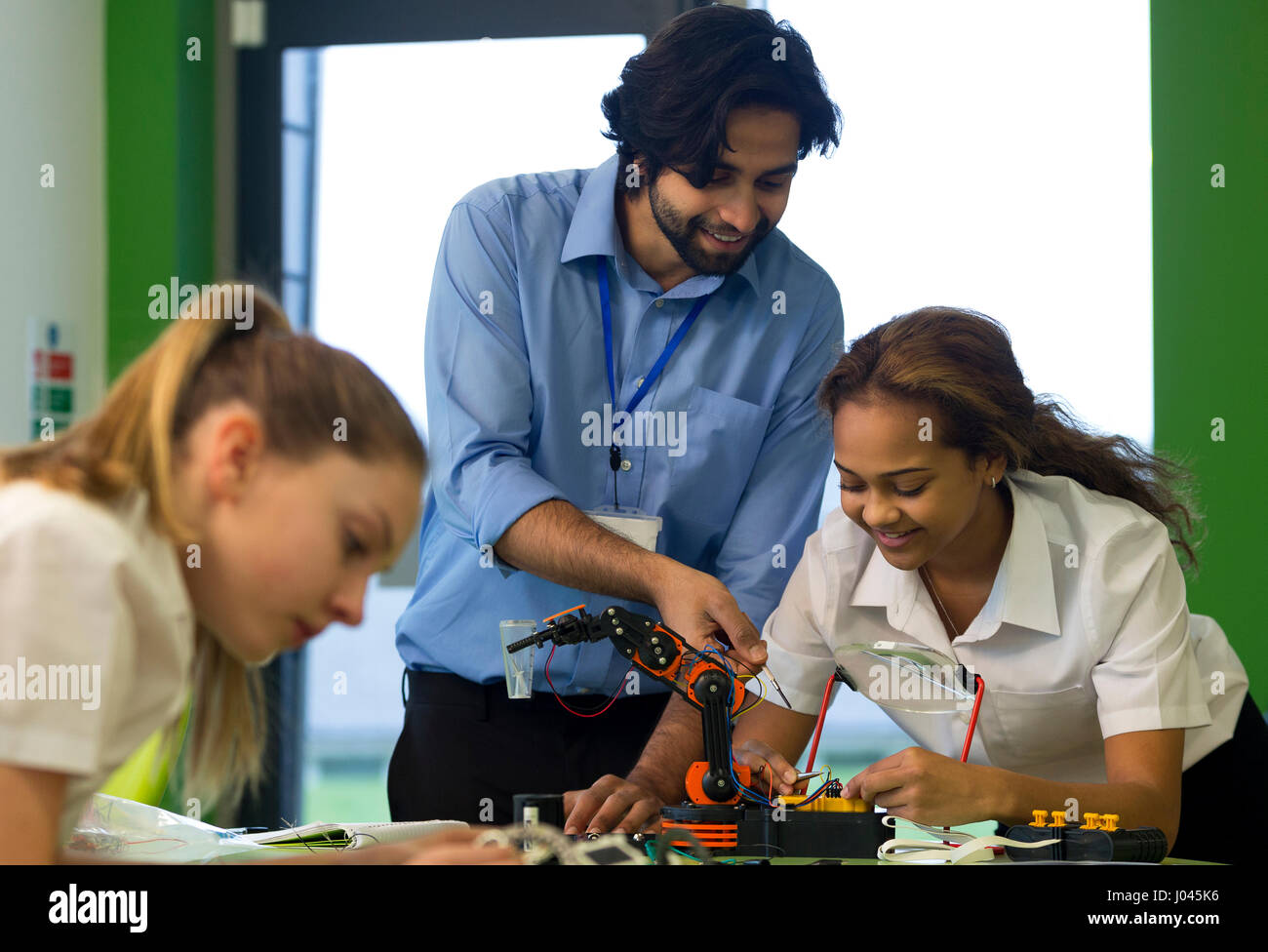 Two students are building a robotic arm in school. The teacher is ...