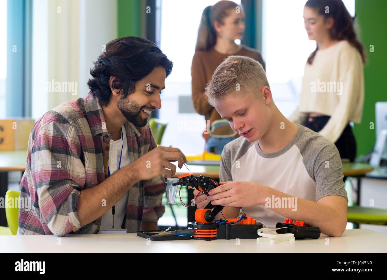 Student and teacher working on a robotic arm in a classroom. There are ...