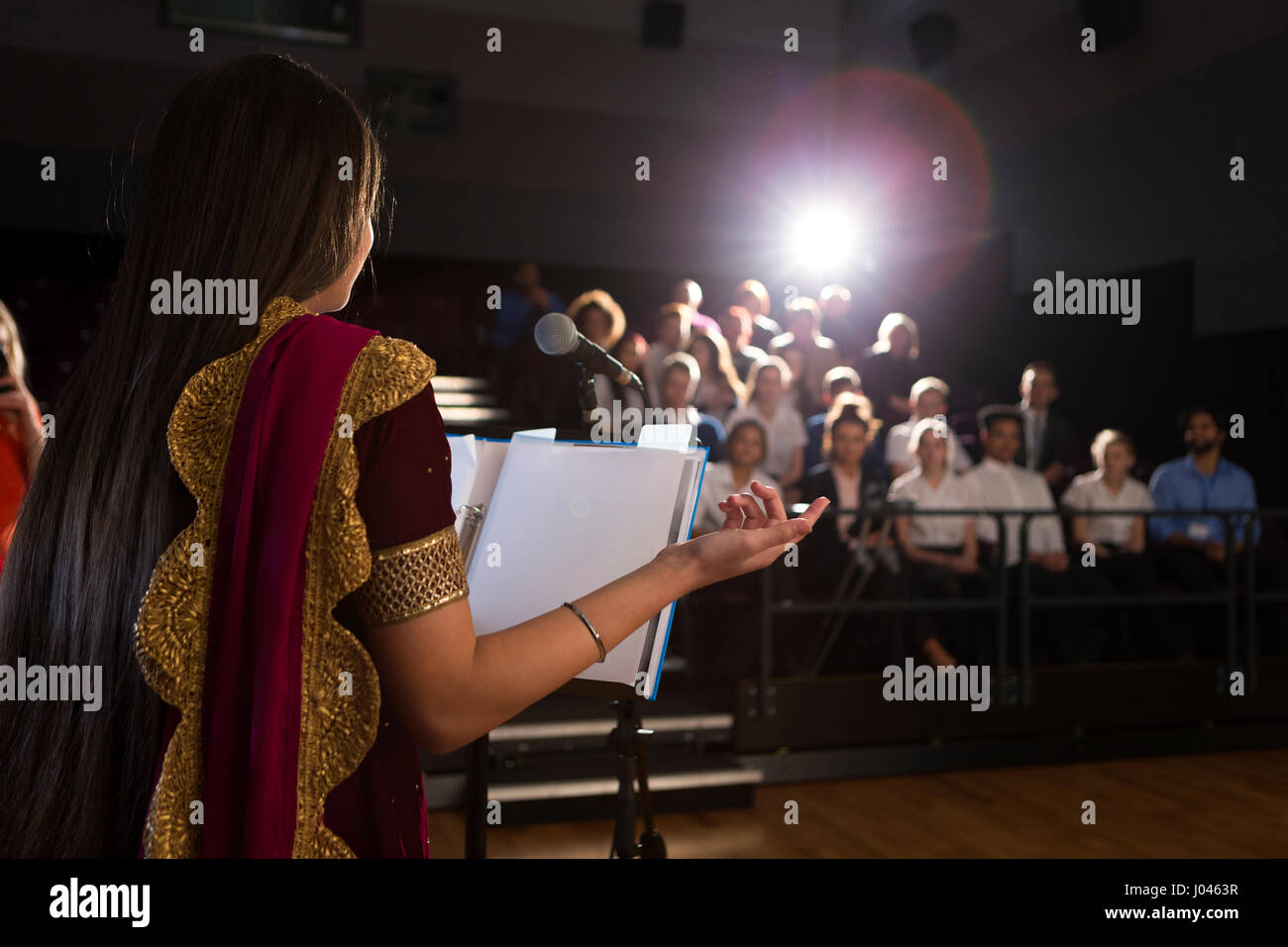 Female student making a speech. She is standing at a podium and talking ...