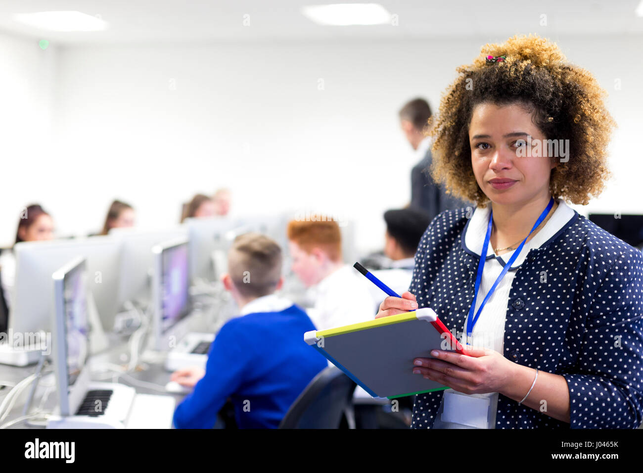 Teacher standing in a classroom with a whiteboard and pen. She is ...