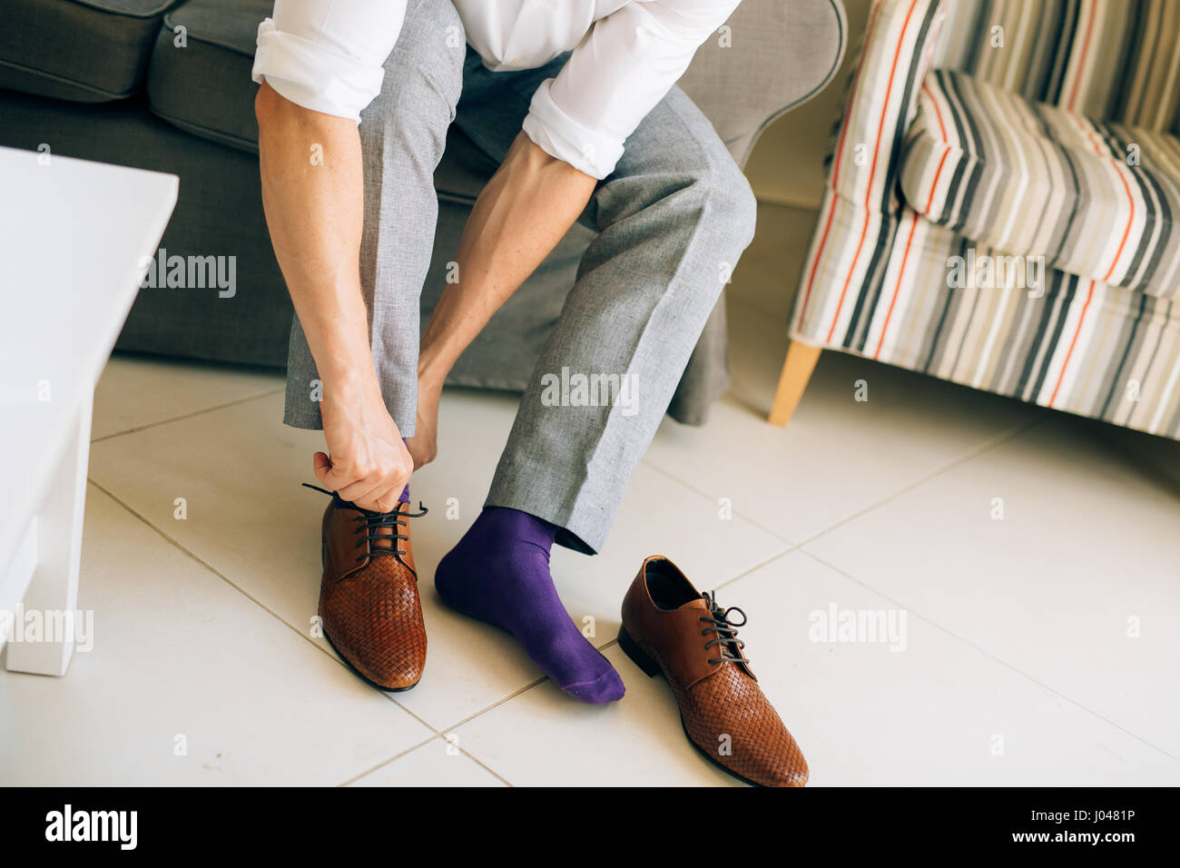 The man in gray slacks and a purple dress socks brown shoes with laces ...