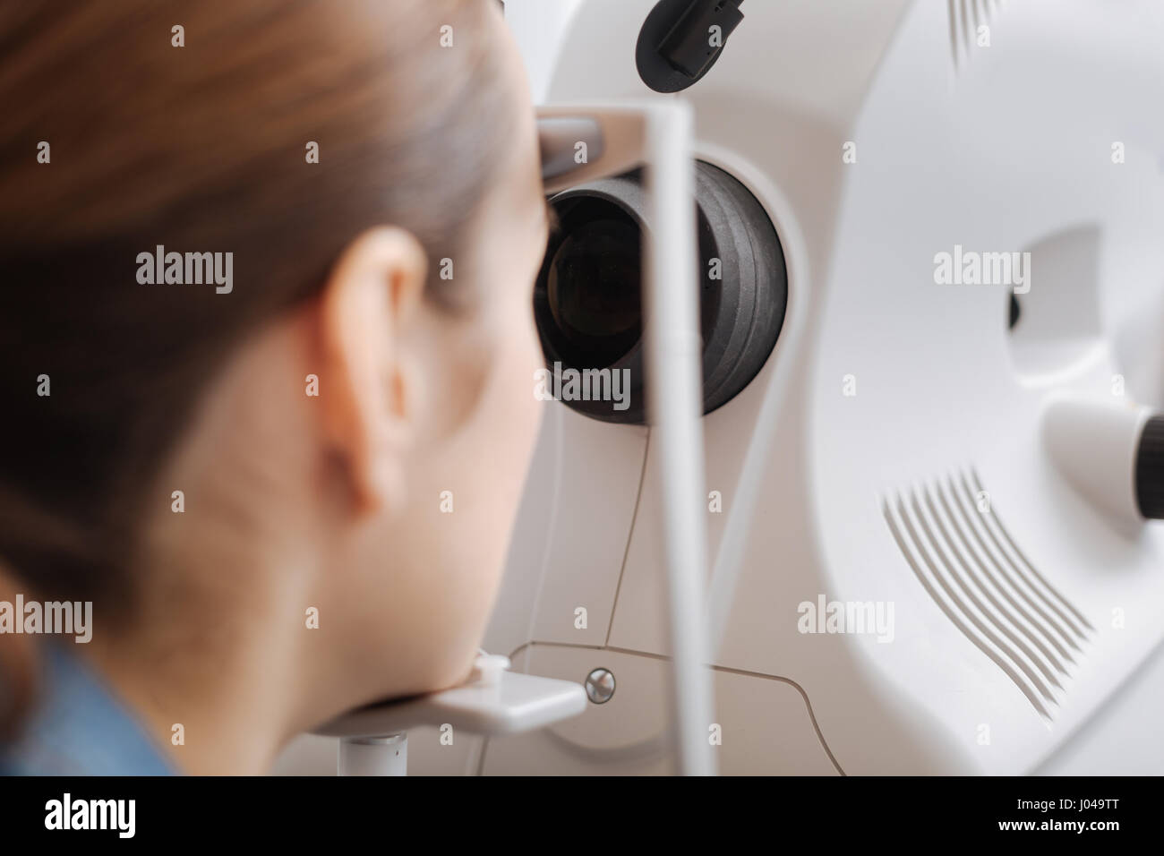 Nice young woman looking into special lens Stock Photo - Alamy