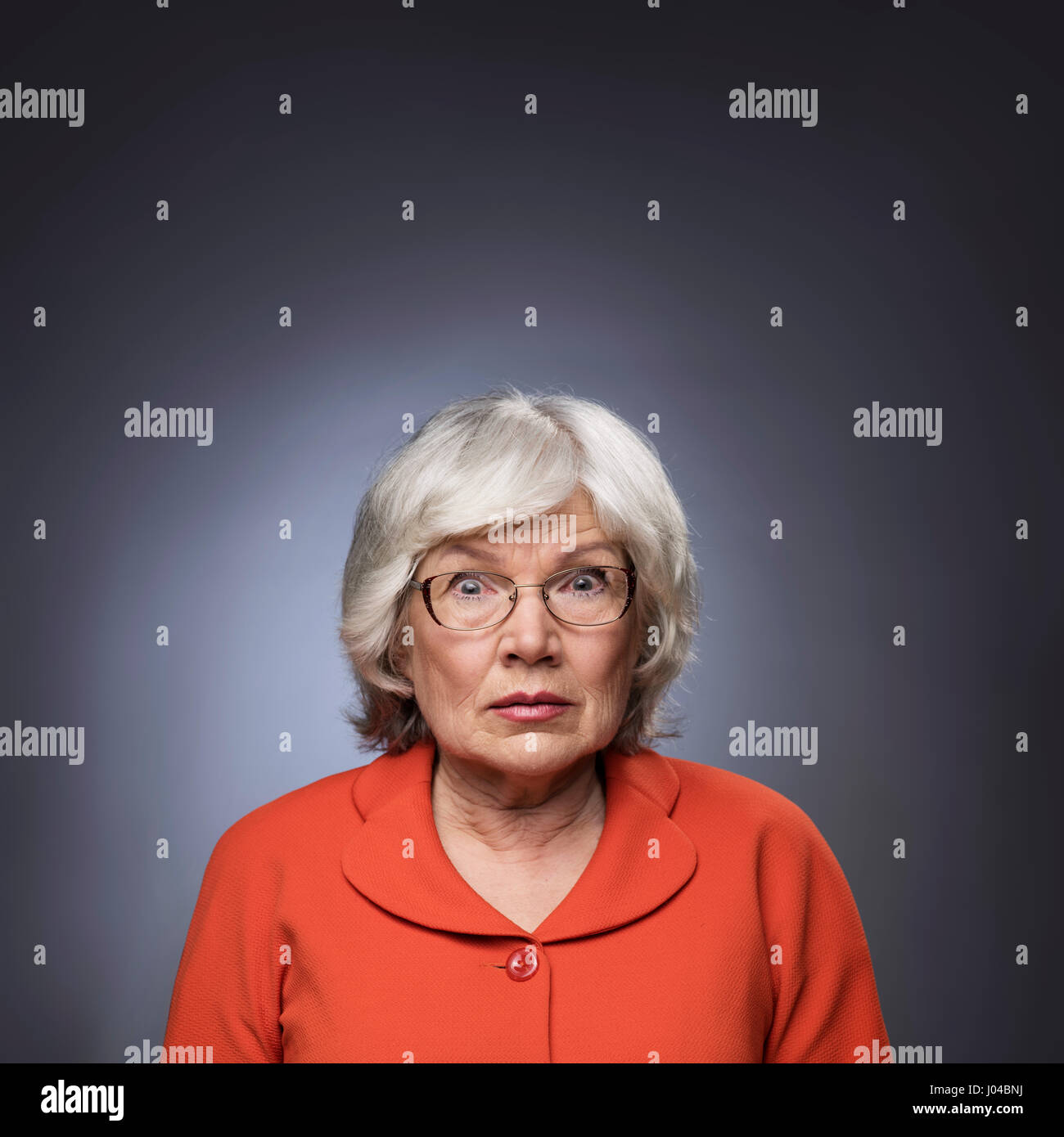 Senior lady staring through her eyeglasses on gray background Stock ...