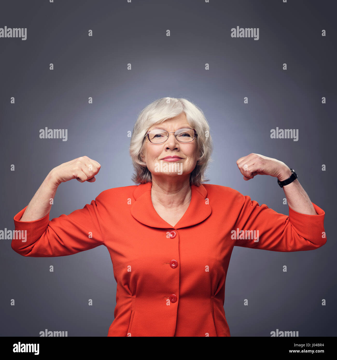 Smiling senior lady showing her muscles on gray background with copy ...