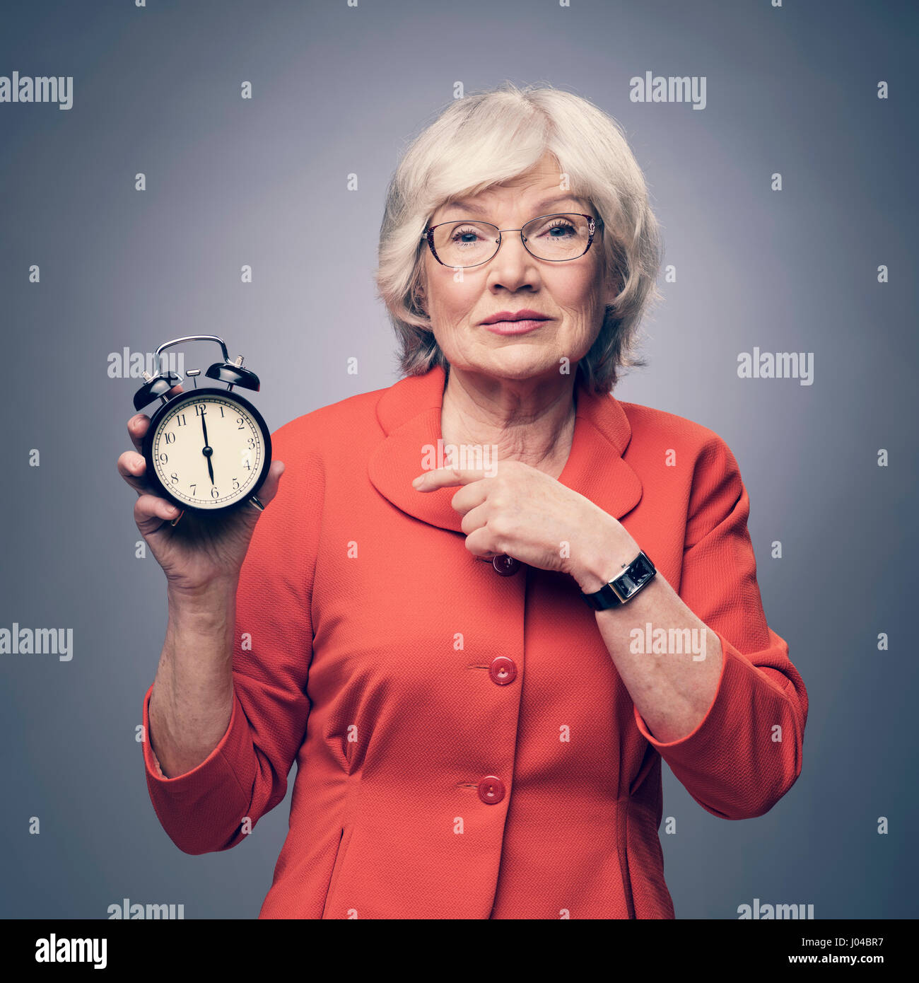 Senior lady pointing to alarm clock showing time of deadline Stock ...