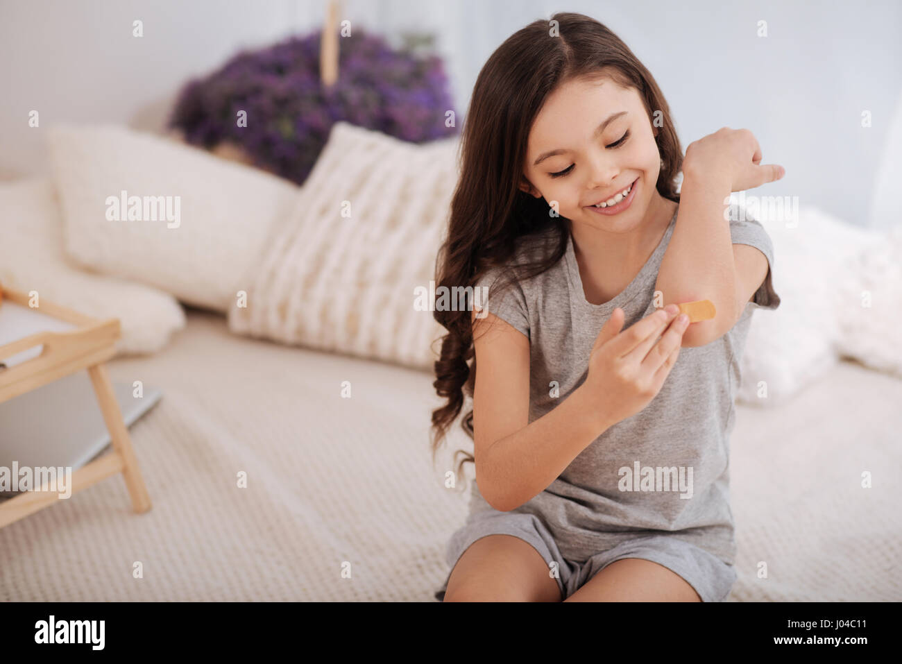 Joyful child treating her wound on the elbow at home Stock Photo - Alamy