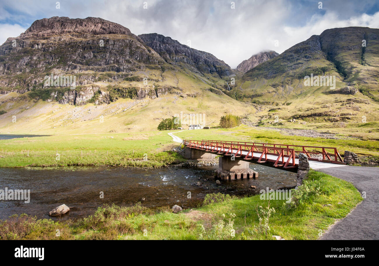 A small bridge crosses the River Coe to Achnambeithach Cottage nestled ...