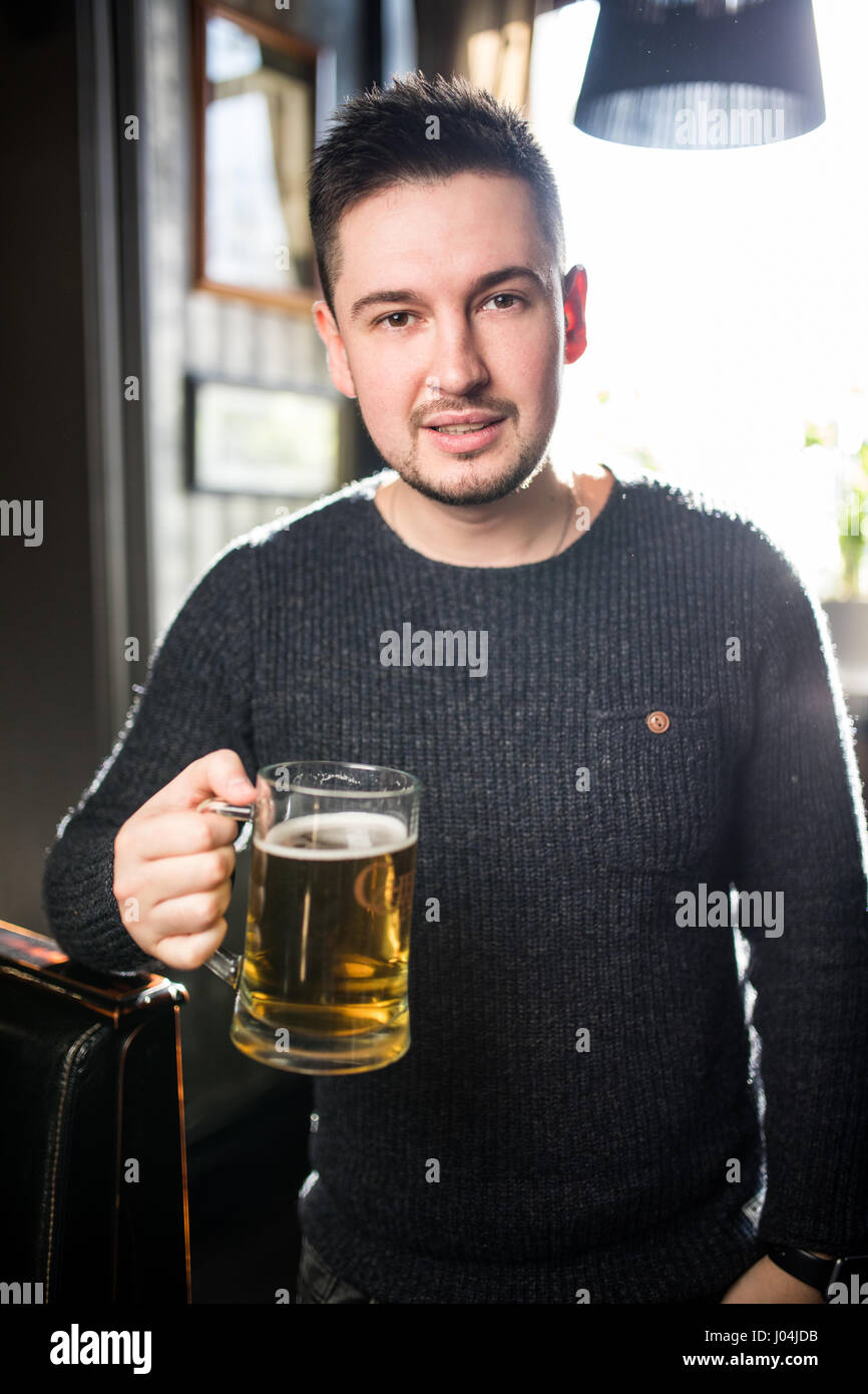 man in a pub or bar holding mug the beer high in the air for cheers in ...